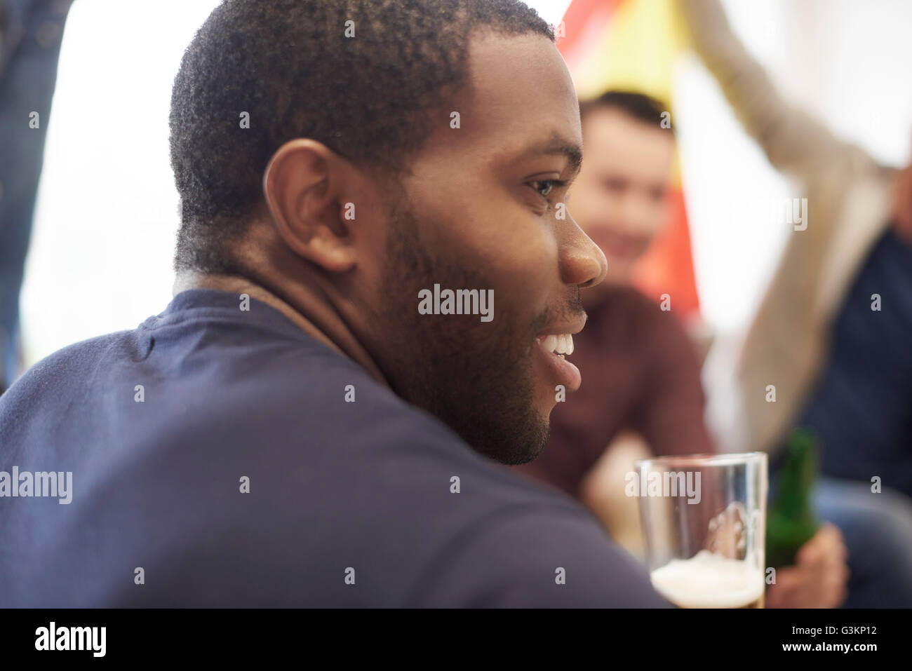 Over the shoulder view of man holding glass of beer looking away ...