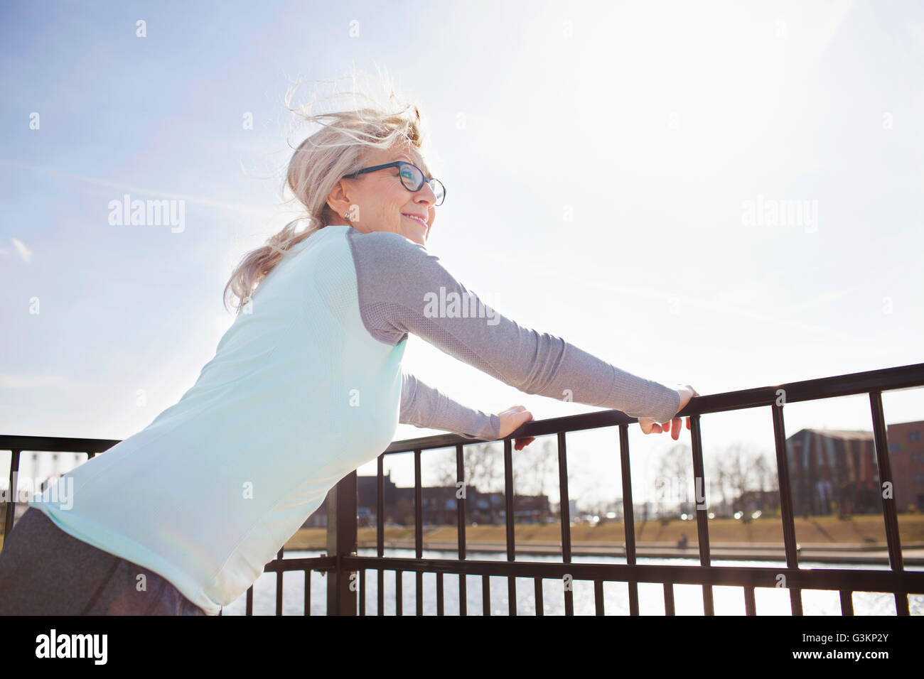 Side view of woman leaning against railing looking away Stock Photo - Alamy