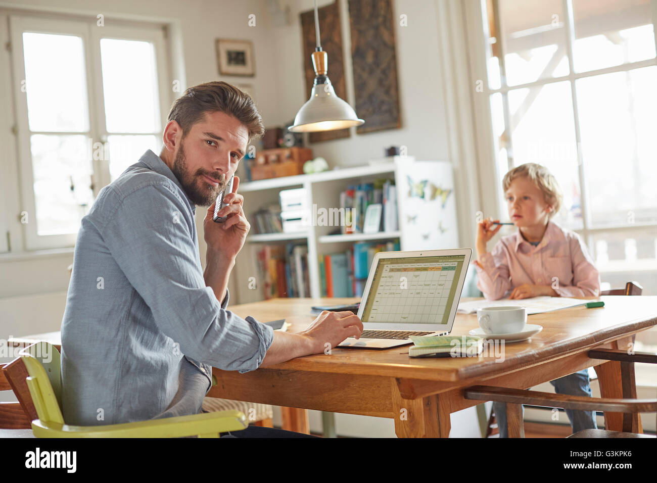 Father on phone while working in home office with son Stock Photo - Alamy