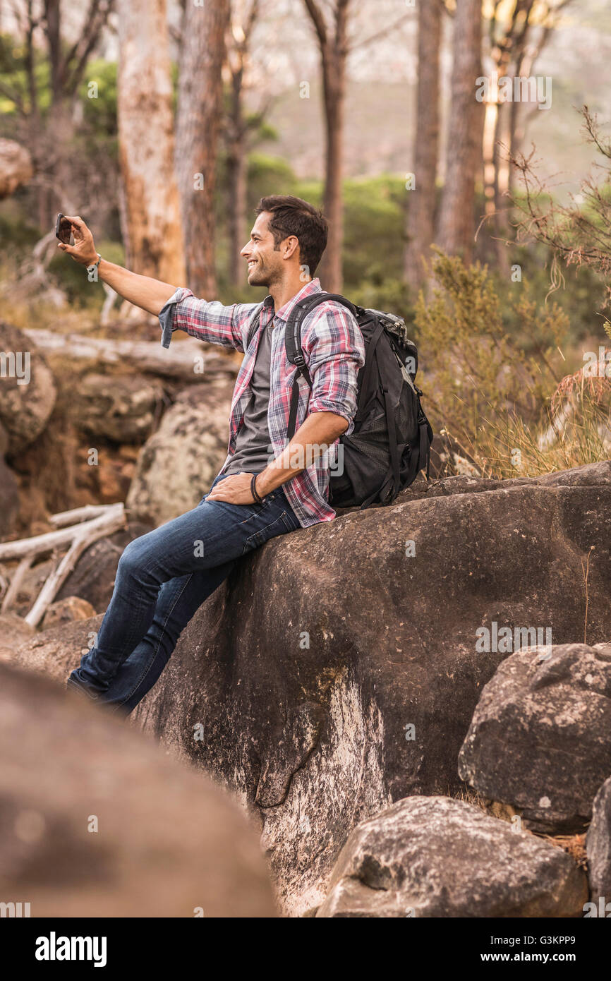 Male hiker taking smartphone selfie on forest rock formation, Deer Park ...
