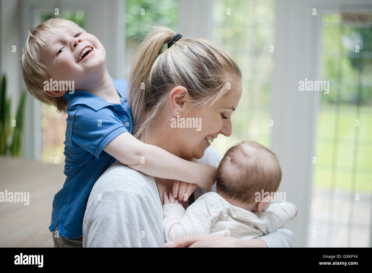 Young boy, arms around his mother's neck, his mother hugging baby boy ...