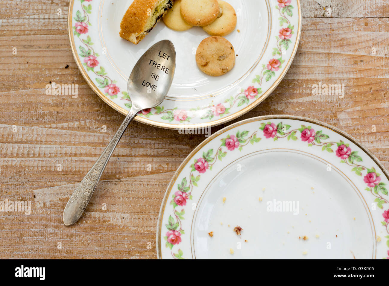 Plates of cookies and spoon engraved with slogan on wooden surface ...