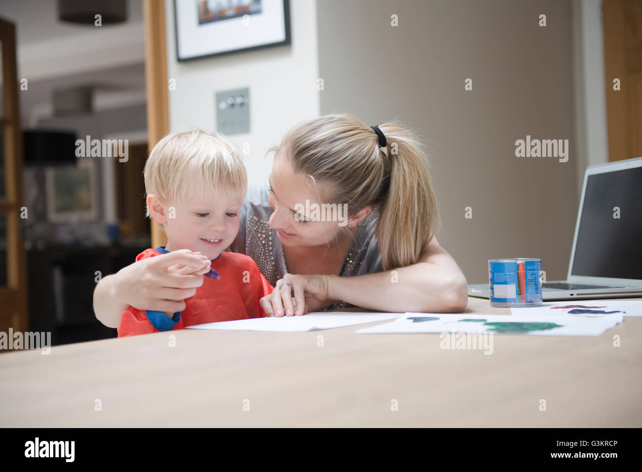 Mother helping son to write Stock Photo - Alamy
