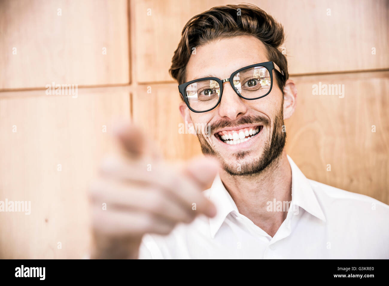 Young man wearing glasses pointing at camera smiling Stock Photo - Alamy