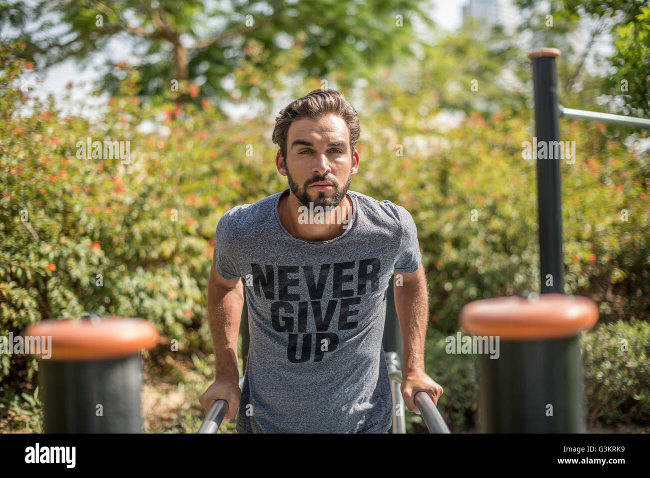 Young man training on park exercise equipment, Dubai, United Arab ...