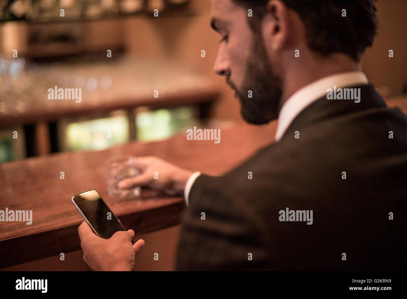 Businessman reading smartphone text at hotel bar Stock Photo - Alamy