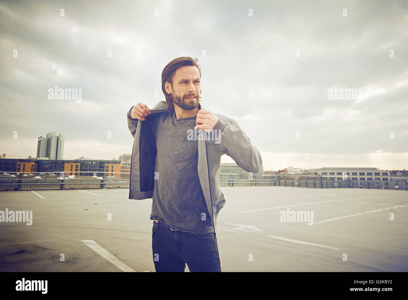Cool mid adult man putting on jacket at rooftop parking lot Stock Photo ...