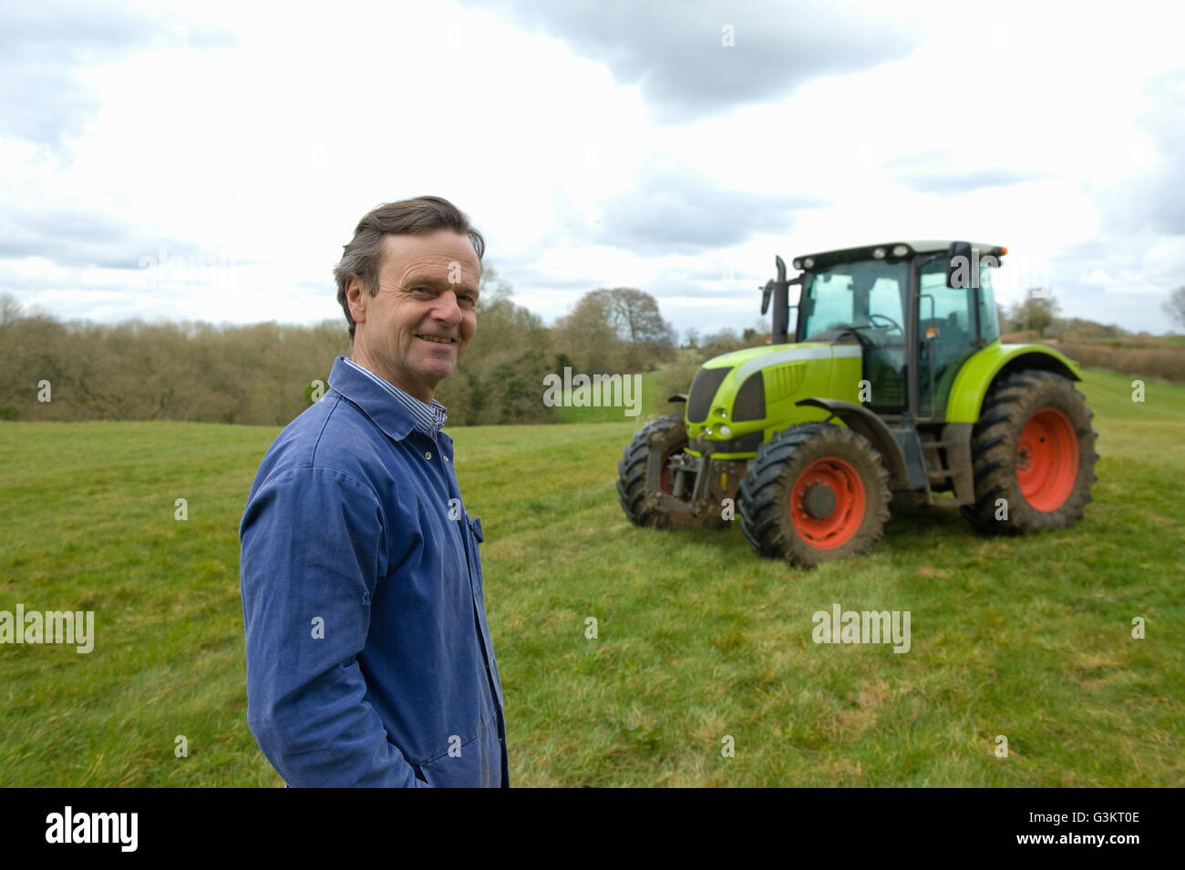 Portrait of farmer in field in front of tractor Stock Photo - Alamy