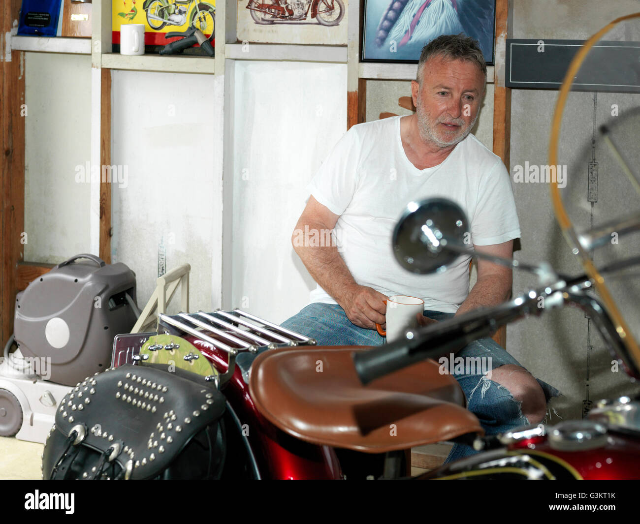 Senior man sitting with a coffee staring at motorcycle in garage Stock ...