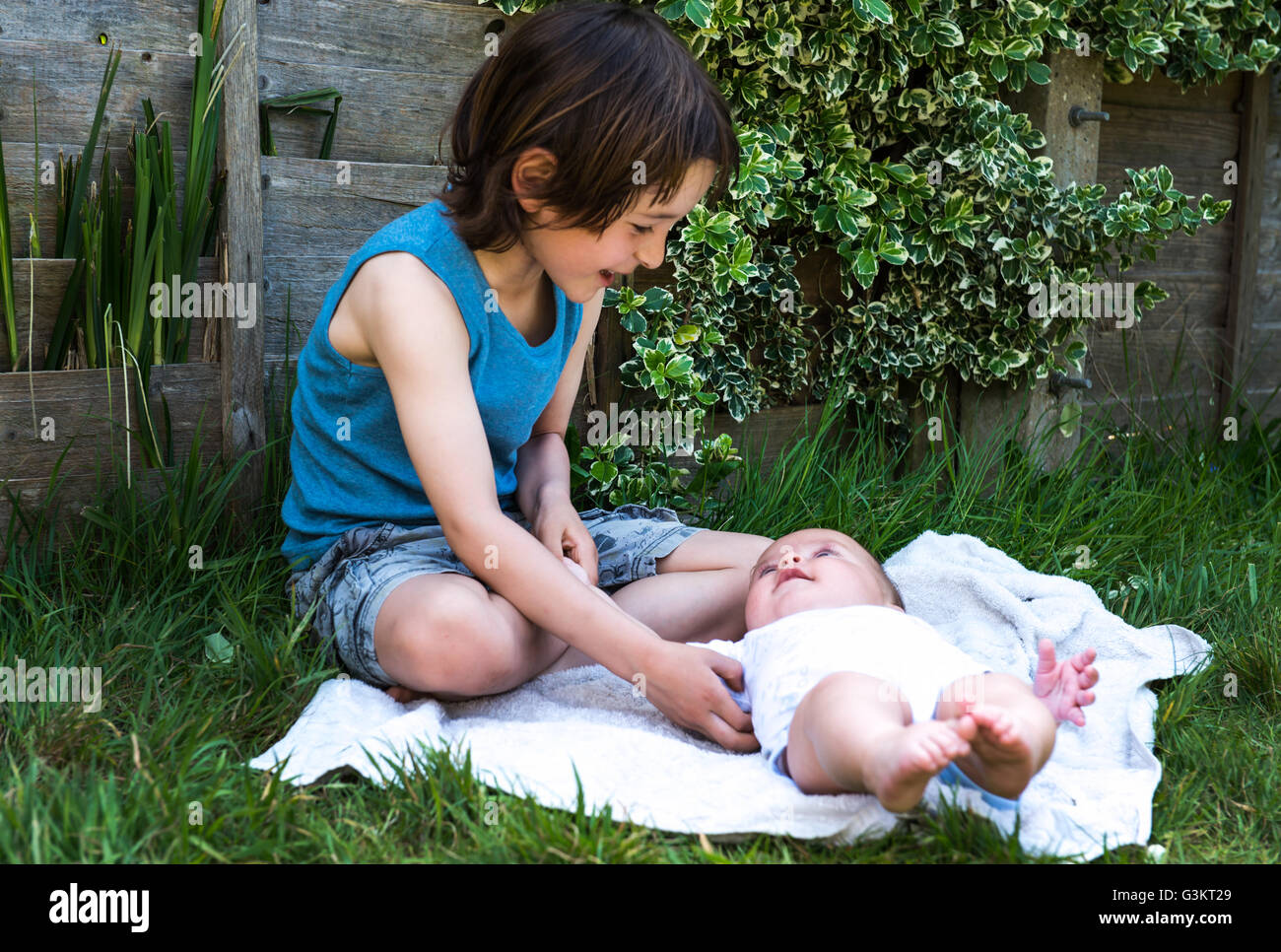 Boy tickling baby brother in garden Stock Photo - Alamy