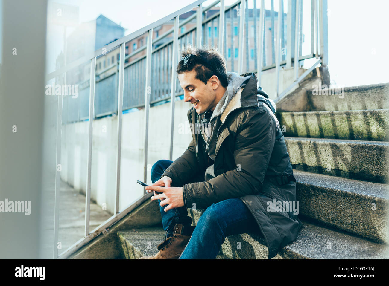 Man sitting on step using smartphone smiling Stock Photo - Alamy