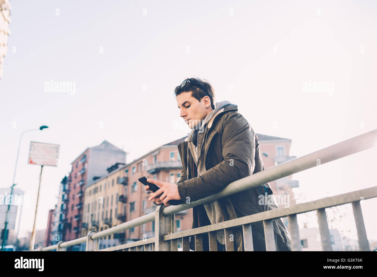 Man leaning against railings using smartphone Stock Photo - Alamy
