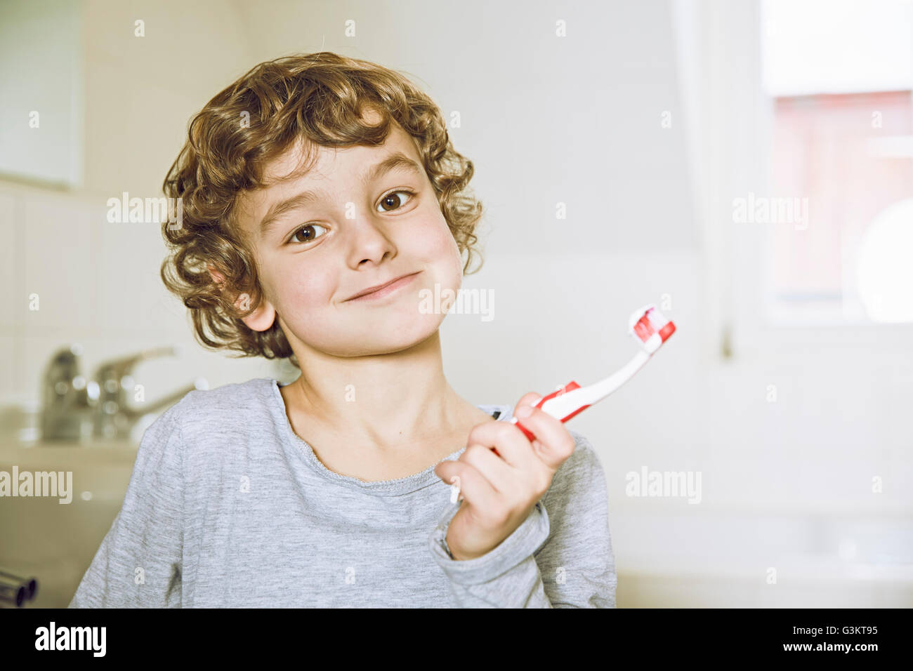 Boy in bathroom holding toothbrush looking at camera smiling Stock ...