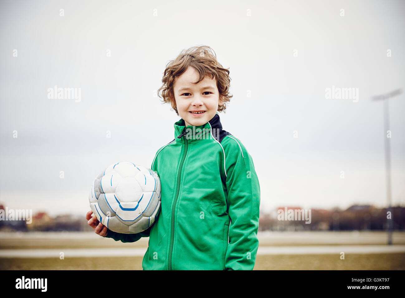 Boy holding football looking at camera smiling Stock Photo - Alamy