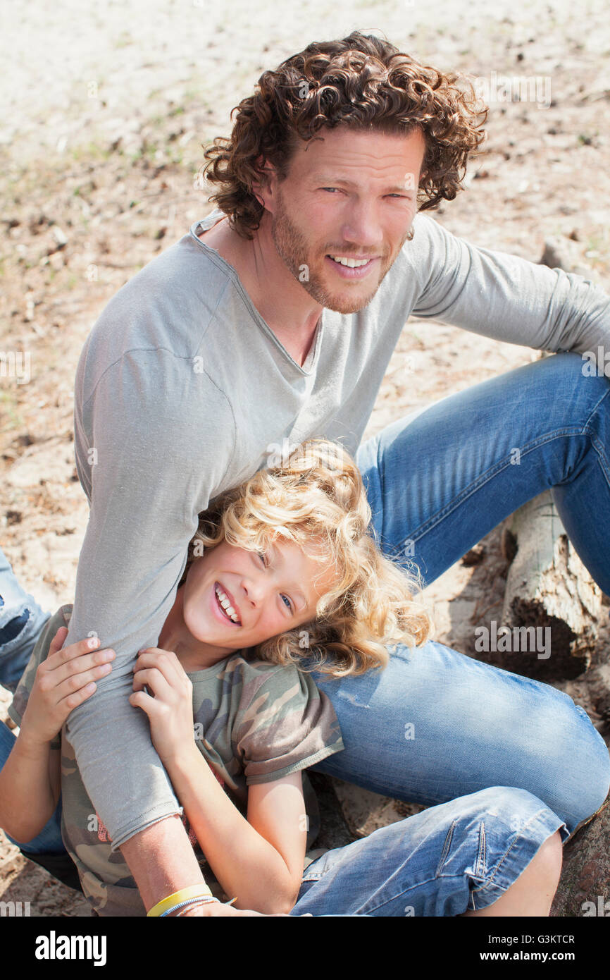 Father sitting with arm around smiling son looking at camera Stock ...