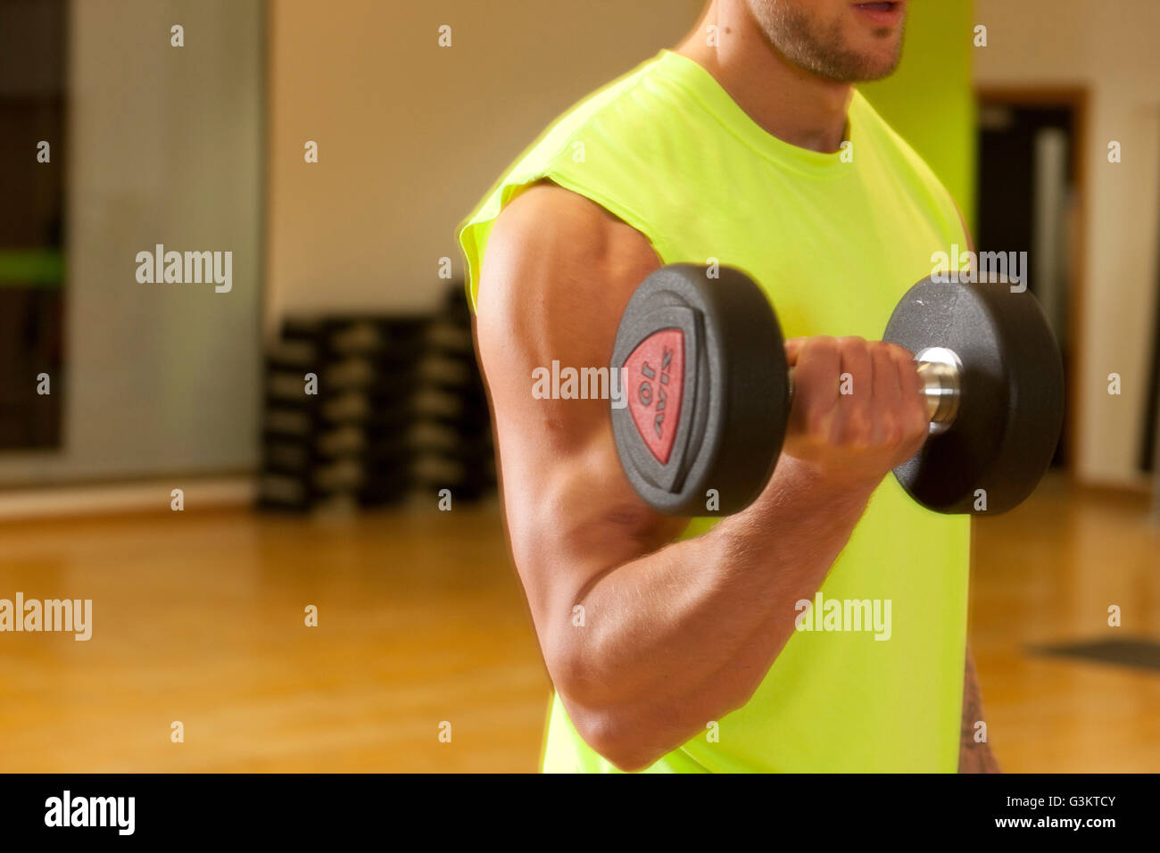 Man in gym using dumbbell Stock Photo - Alamy