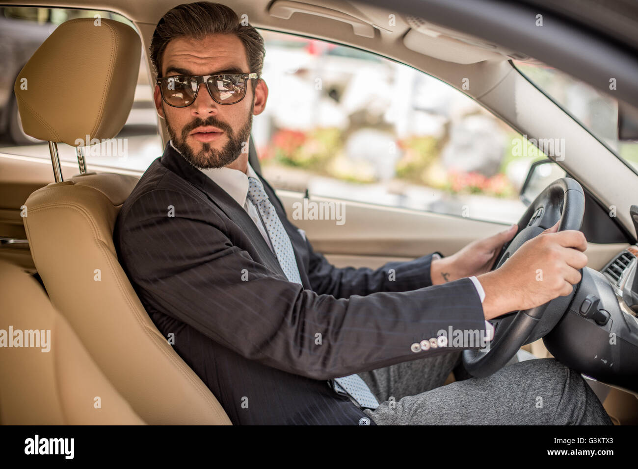 Young businessman driving car looking over his shoulder, Dubai, United ...