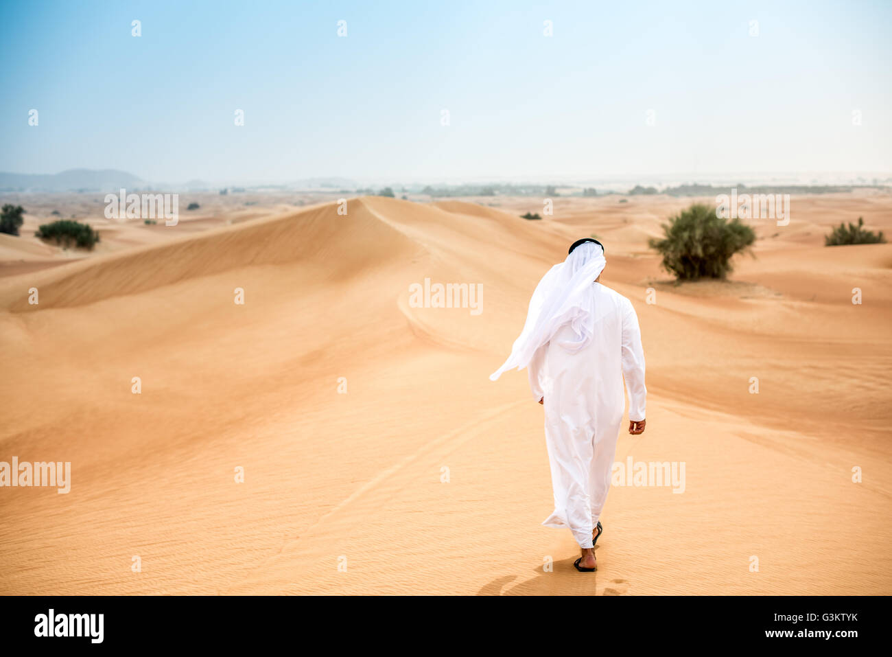 Rear view of middle eastern man wearing traditional clothes walking in ...