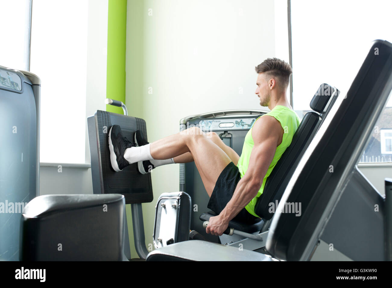 Side view of young man in gym using exercise equipment Stock Photo - Alamy