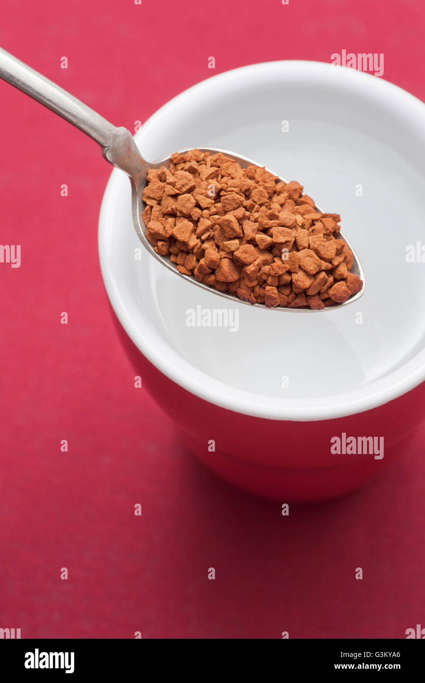 Spoon with instant coffee and cup filled with hot water Stock Photo - Alamy