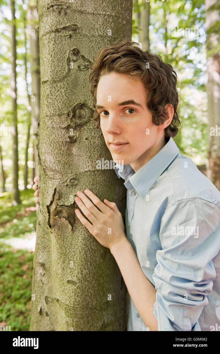 Young man standing by a tree in the woods Stock Photo - Alamy