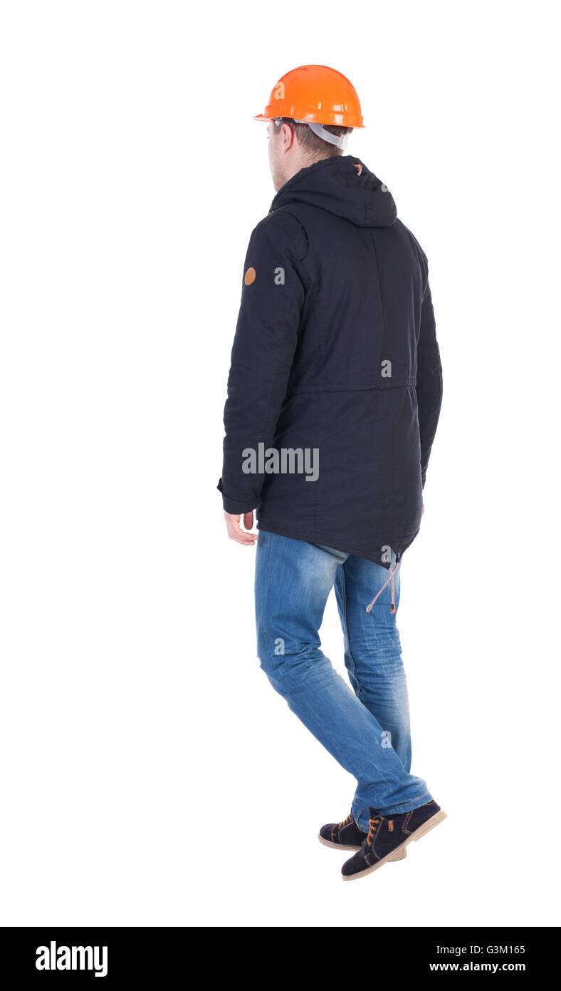 Back view of goingWorker in a helmet. walking young engineer. Rear view ...