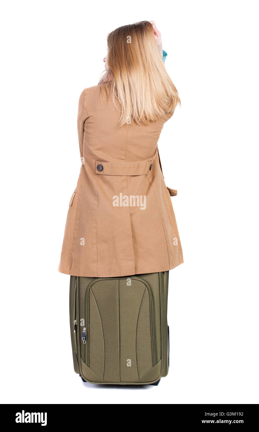 back view of woman in cloak sits on a suitcase. beautiful girl in ...