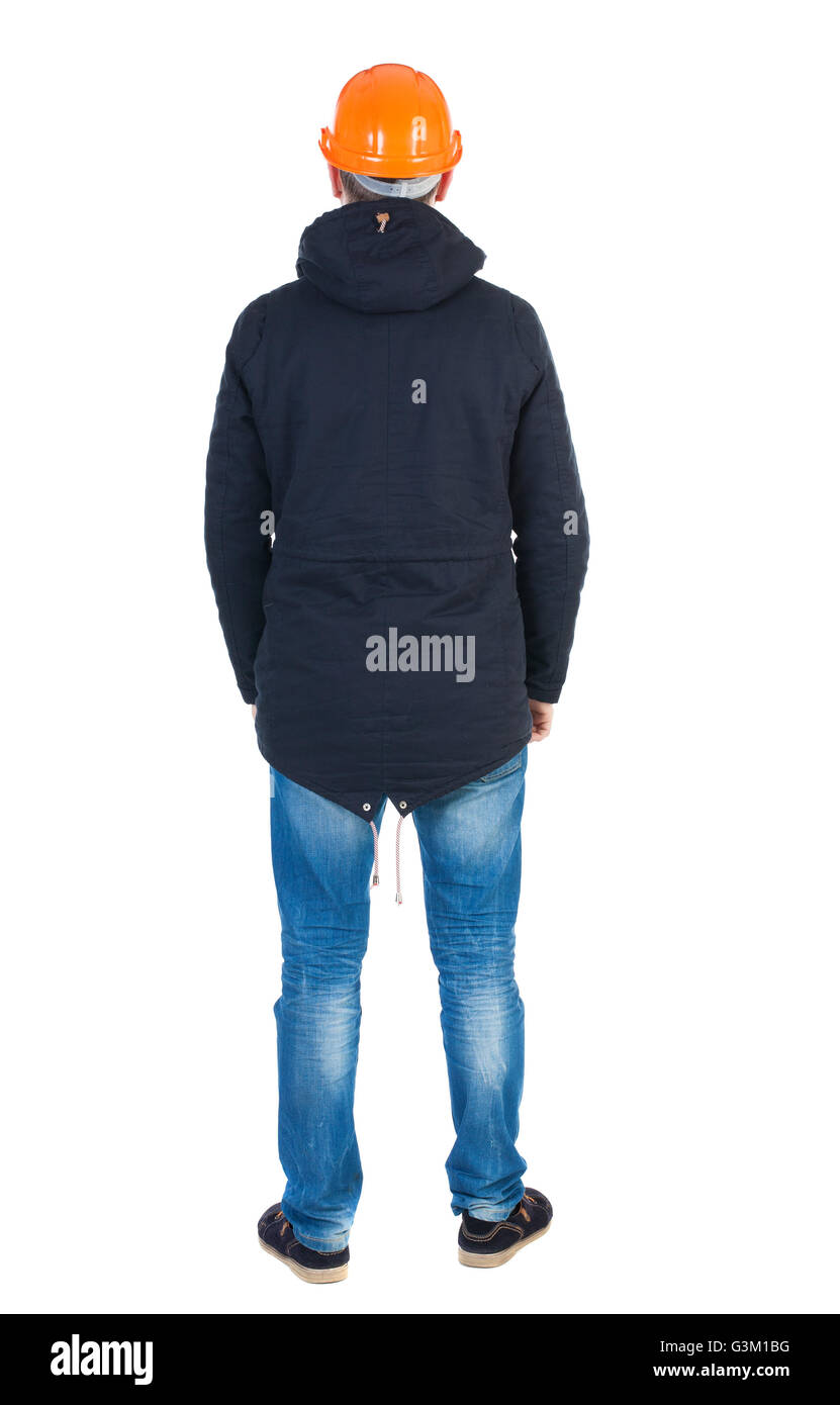Backview of an engineer in jacket and construction helmet stands ...