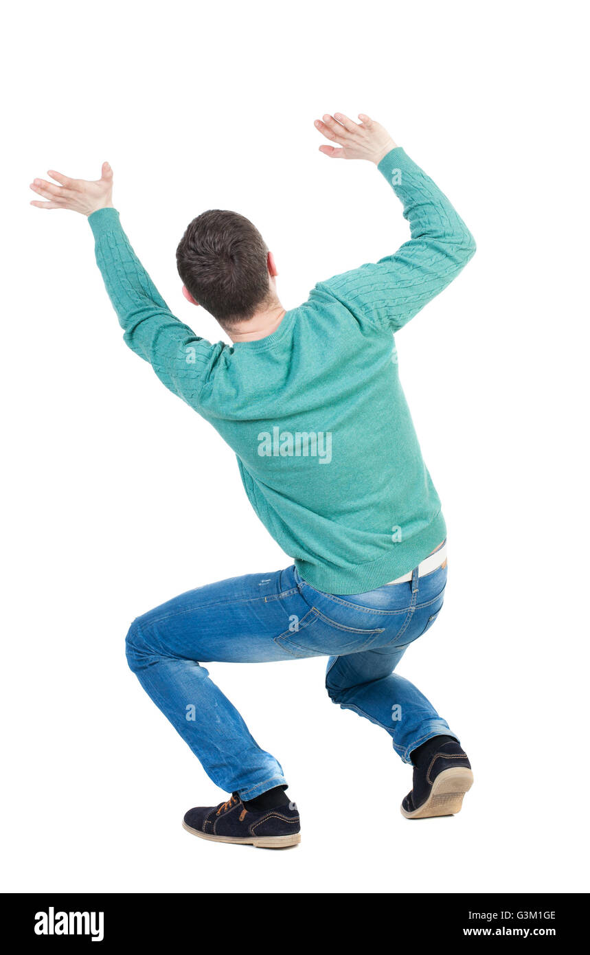 back view. man protects hands from what is falling from above. Man ...