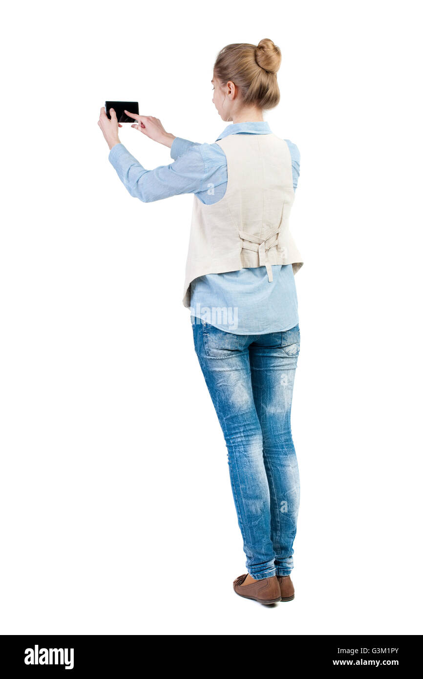 back view of standing young beautiful woman in vest and using a mobile ...