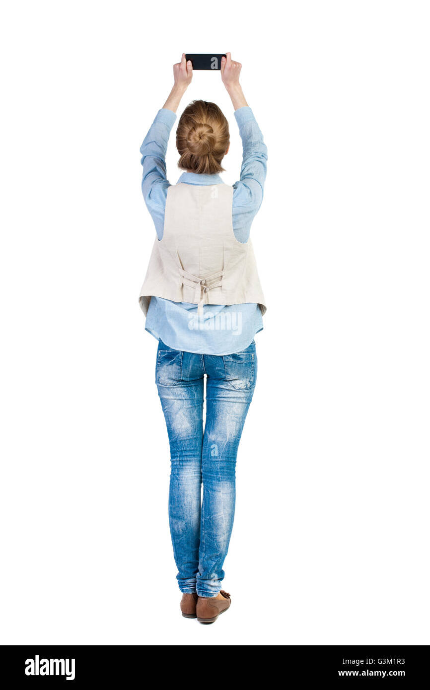 back view of standing young beautiful woman in vest and using a mobile ...