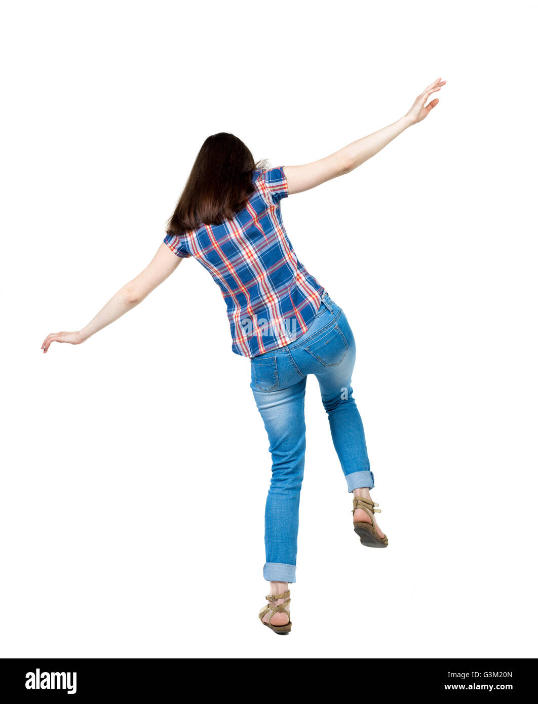 Back view woman Balances waving his arms. Standing young girl in jeans ...