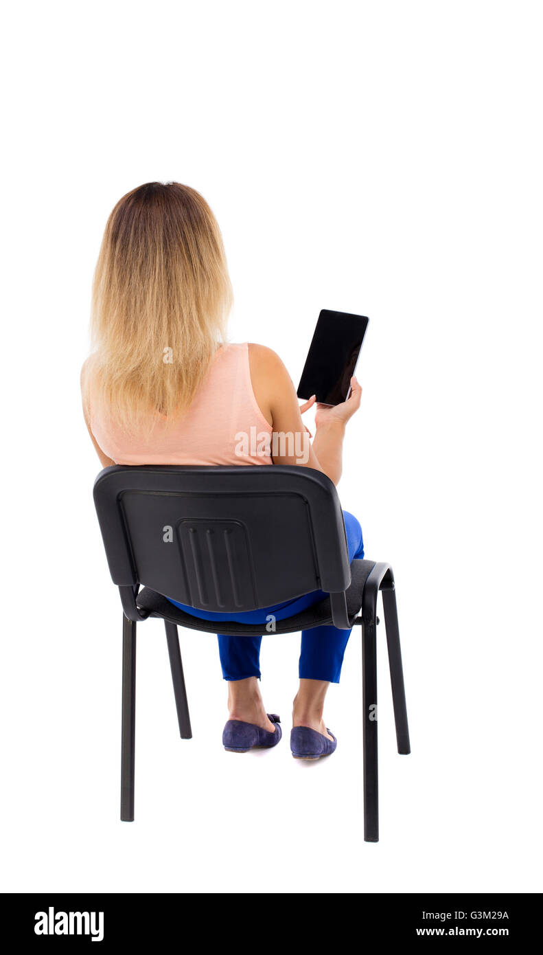 back view of woman sitting on chair and looks at the screen of the ...