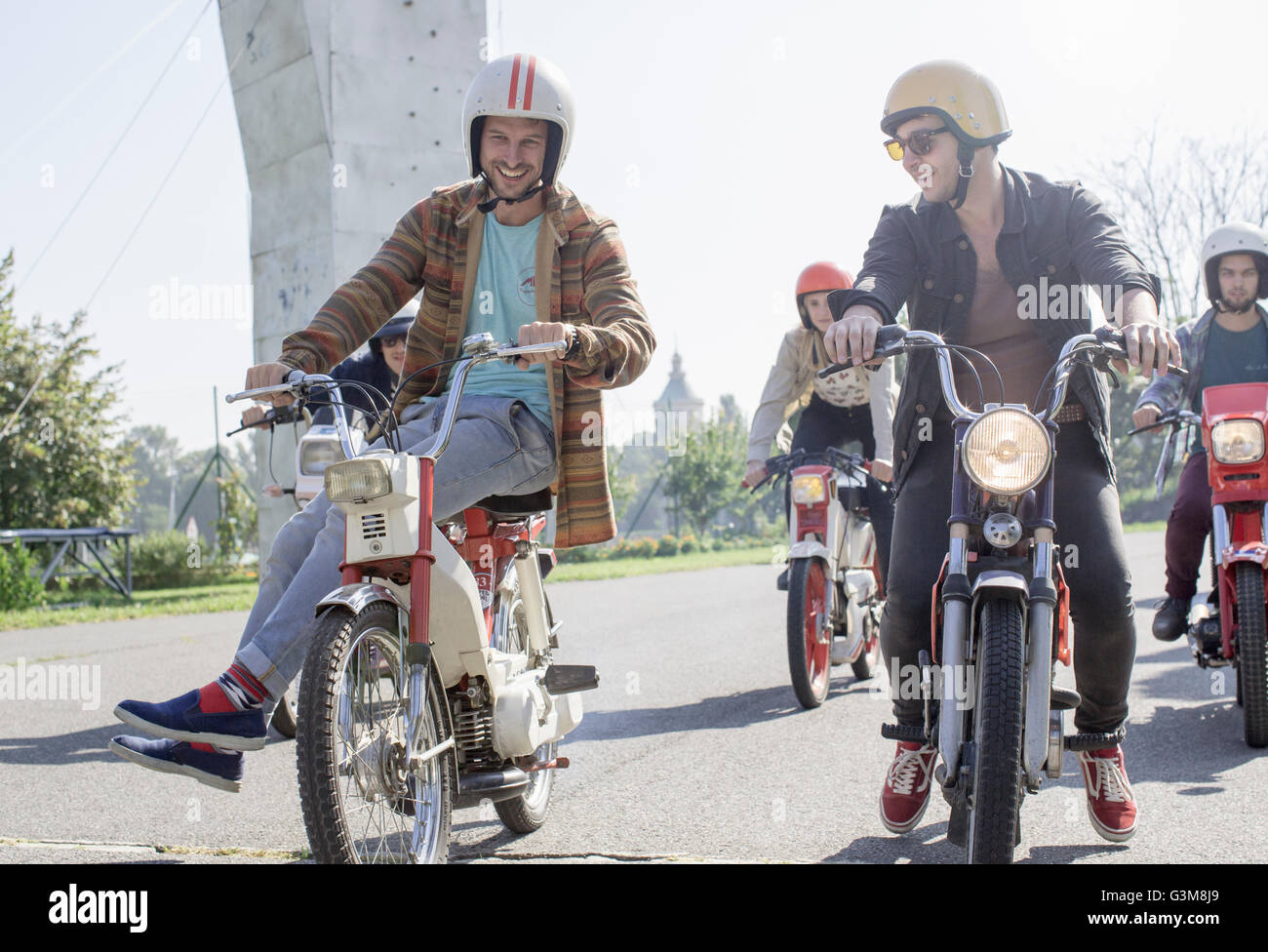 Group of friends riding mopeds along road Stock Photo - Alamy