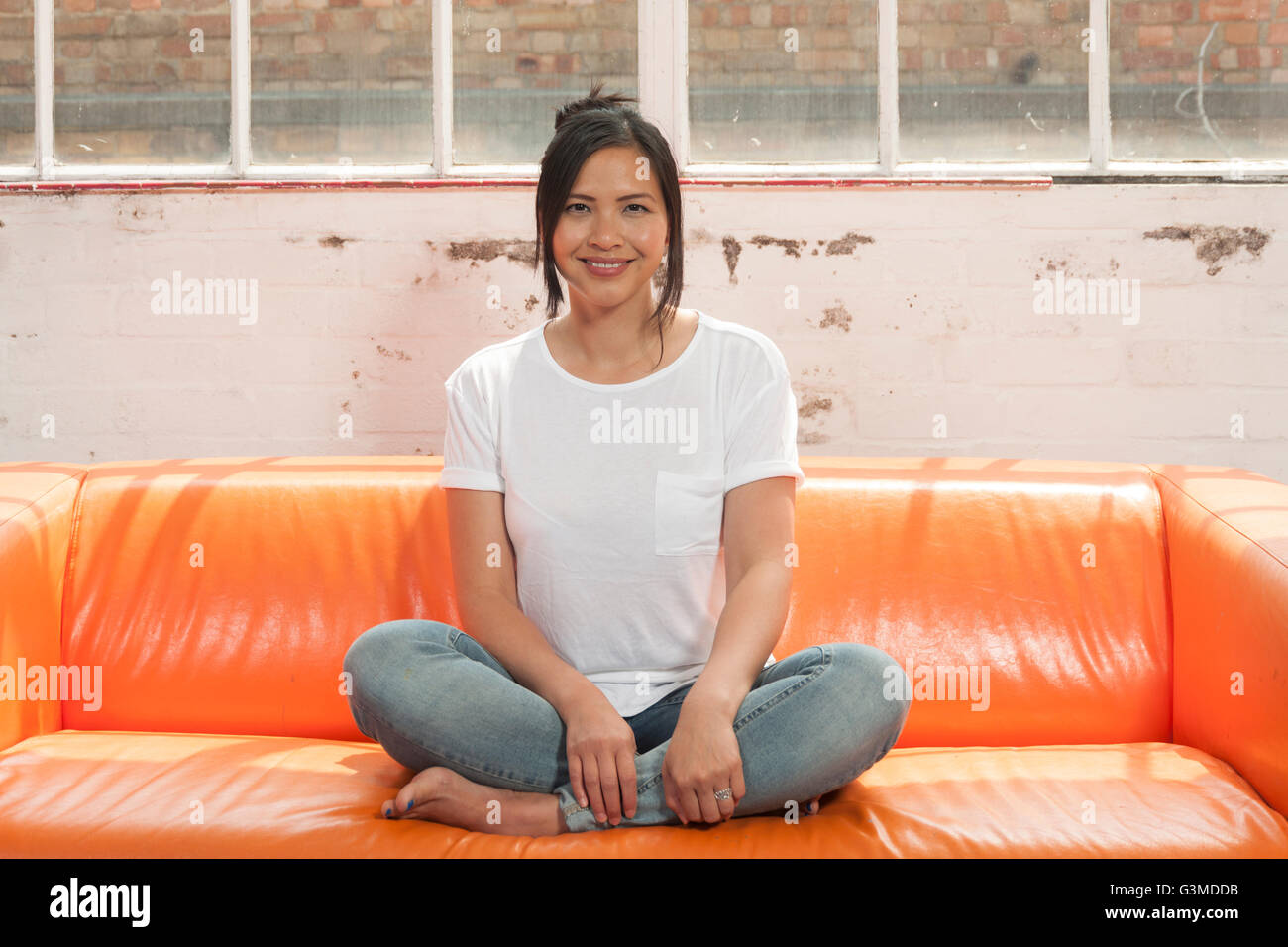 Woman sitting crossed legged on a sofa relaxing and smiling Stock Photo ...