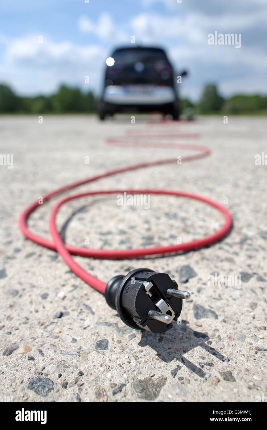 Symbolic image - A red electric cable behind a BMW i3 electric car on a ...