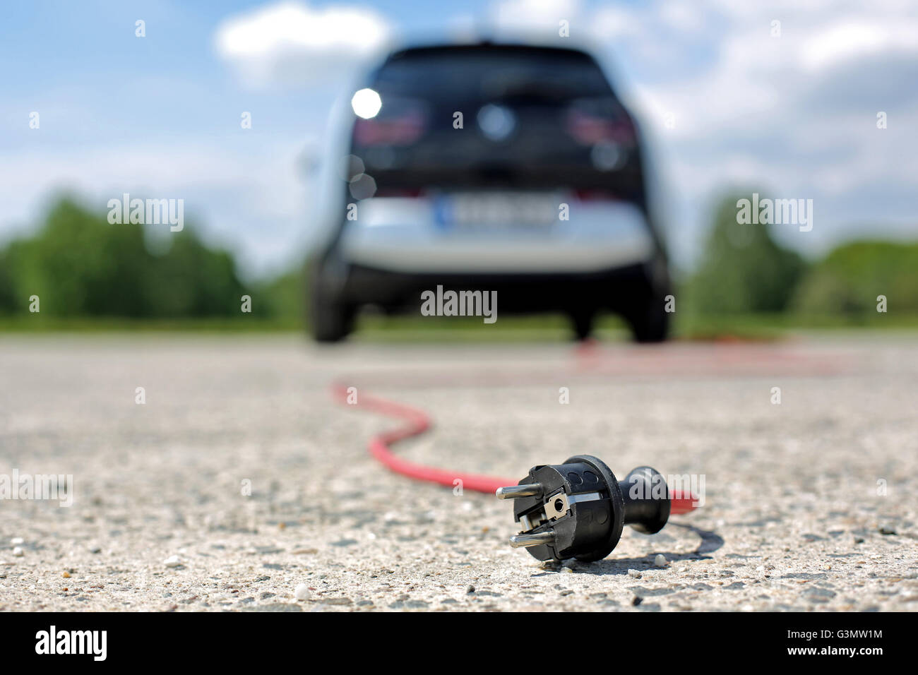 Symbolic image - A red electric cable behind a BMW i3 electric car on a ...