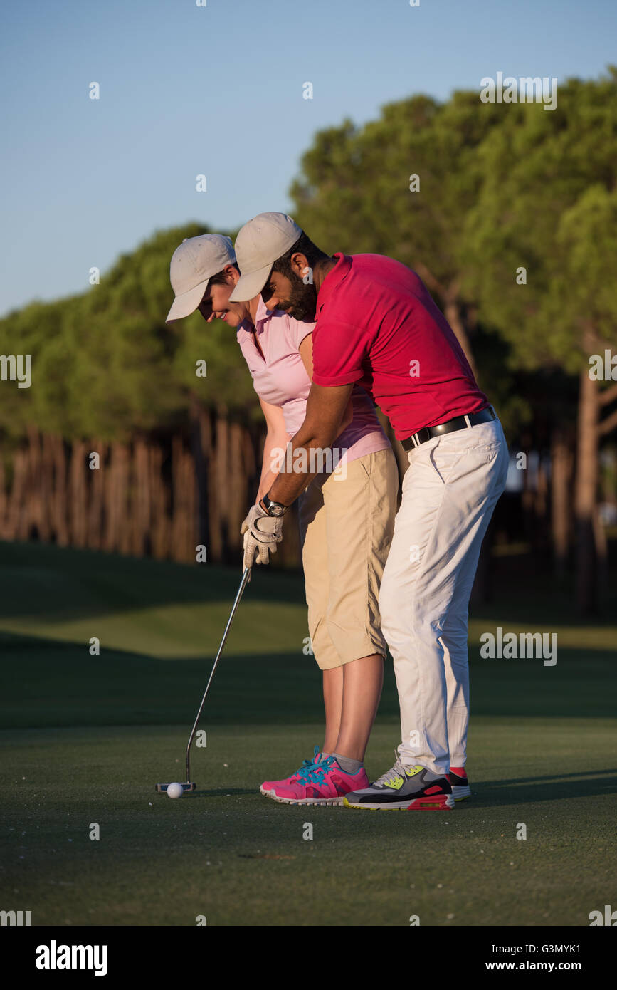 male golf instructor teaching female golf player, personal trainer ...