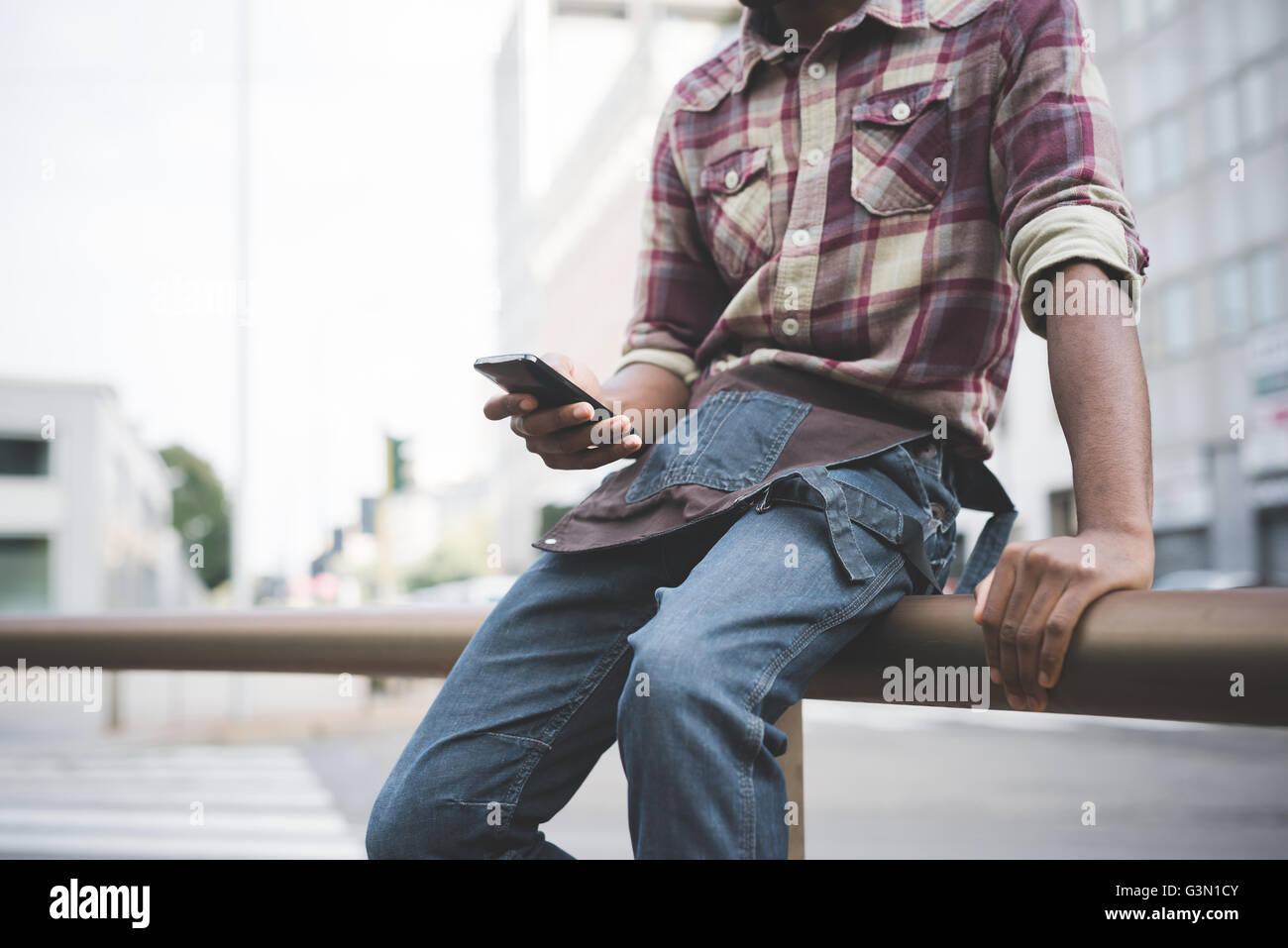 Close up on the hand of a young handsome afro black man using a smartphone, tapping the screen ...