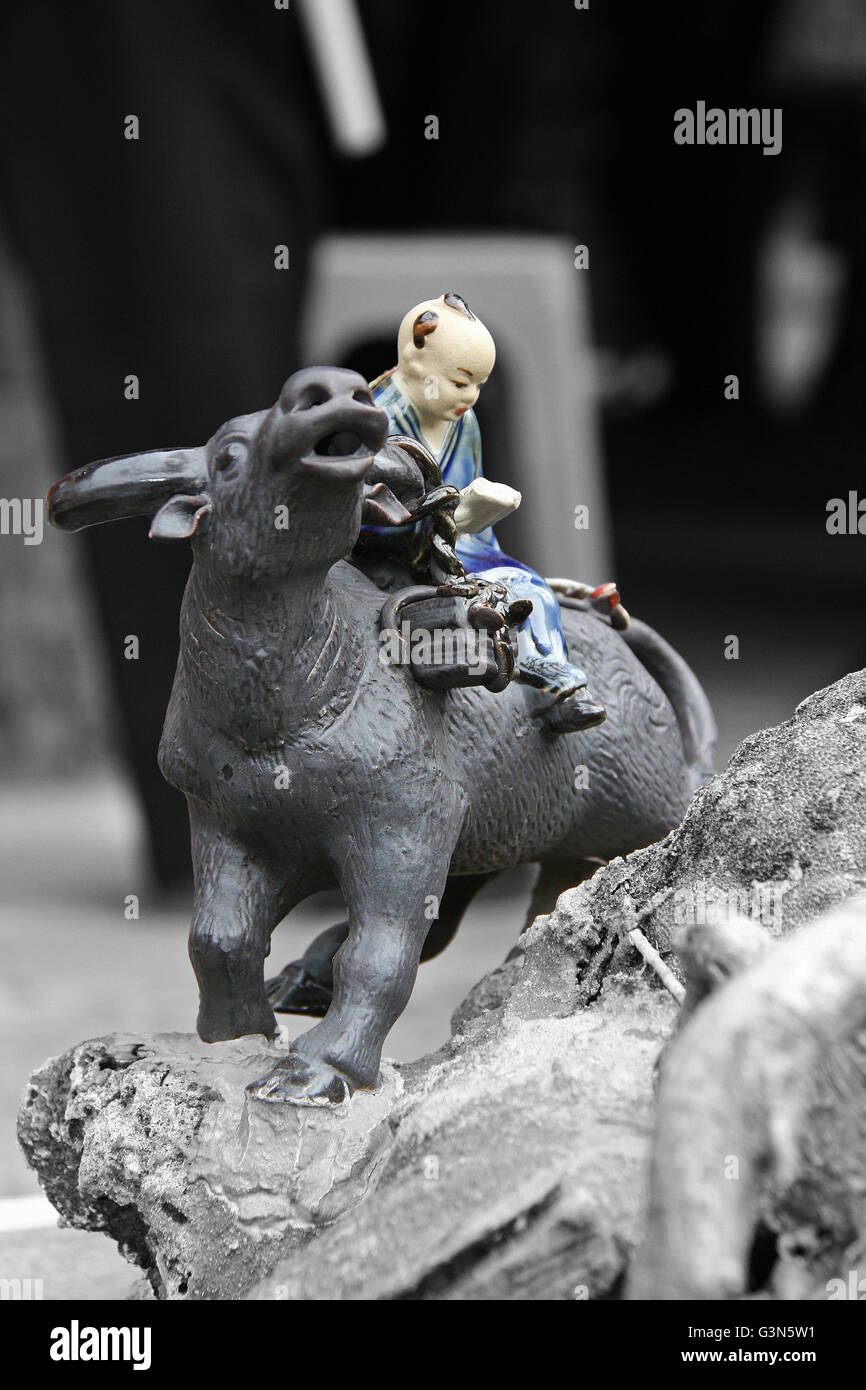 Statue representing a child sat on the back of a water buffalo in a ...