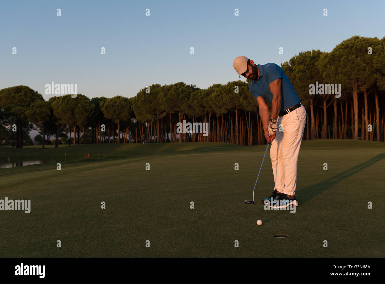 golfer hitting ball shot with driver on golf course at beautiful sunset ...