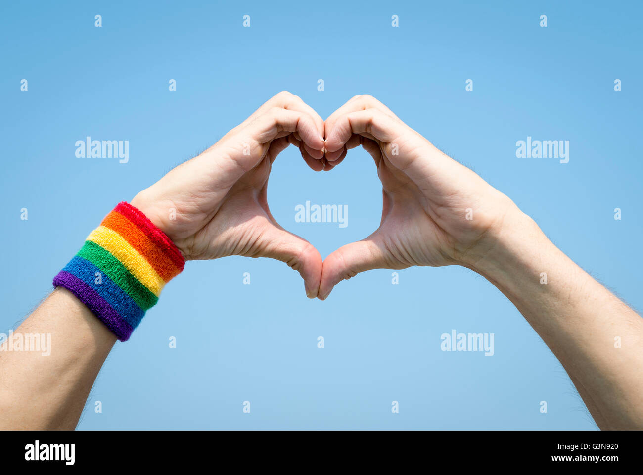 Gay athlete making hand heart with gay pride rainbow colors wristband ...