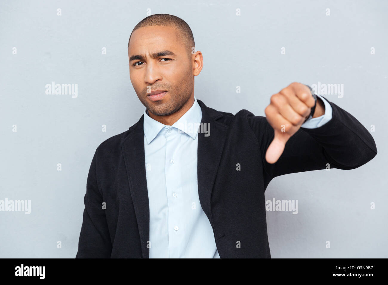 Young guy showing thumbs down sign isolated on the gray background ...