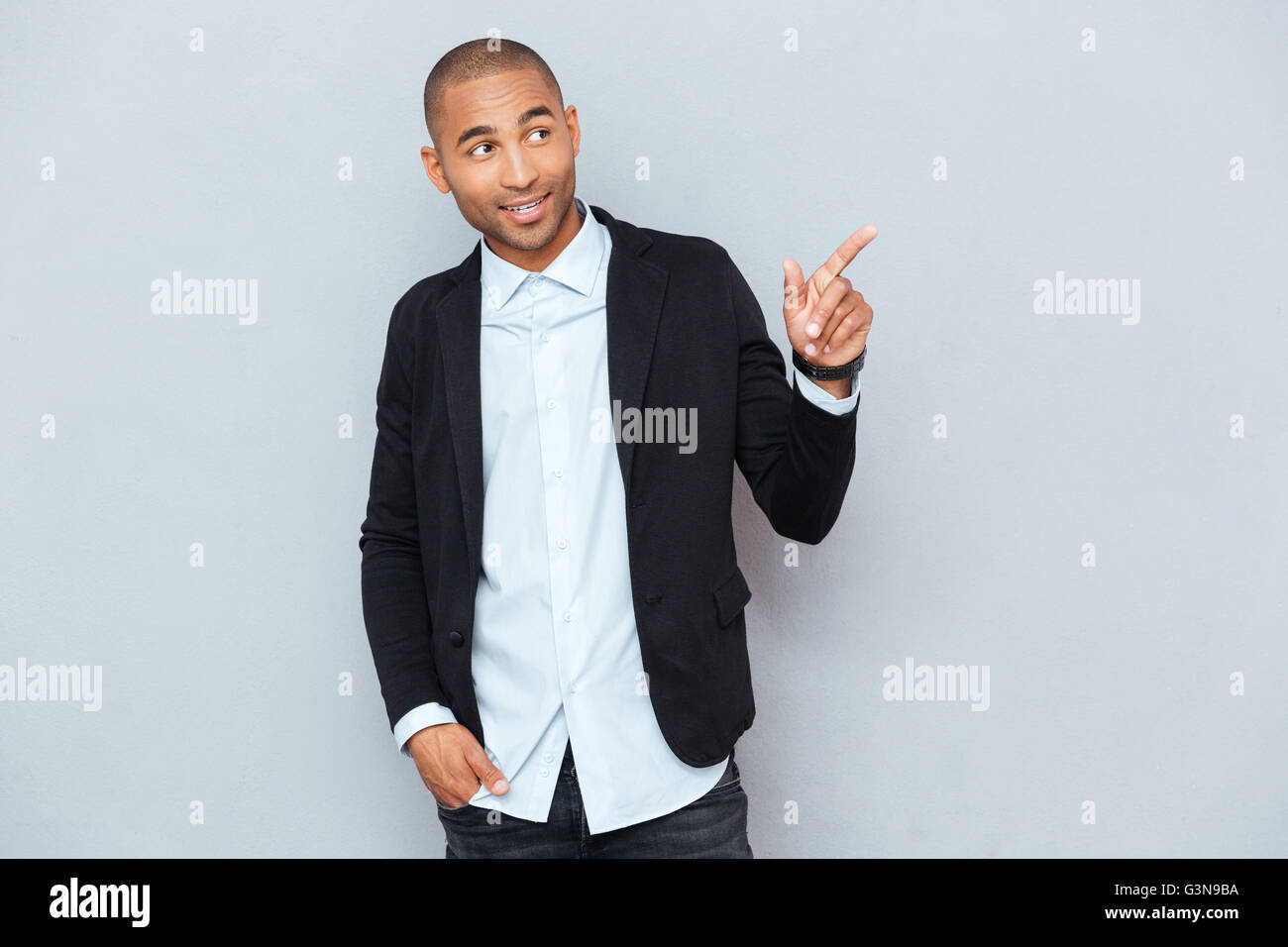Portrait of a happy young man pointing at something interesting ...
