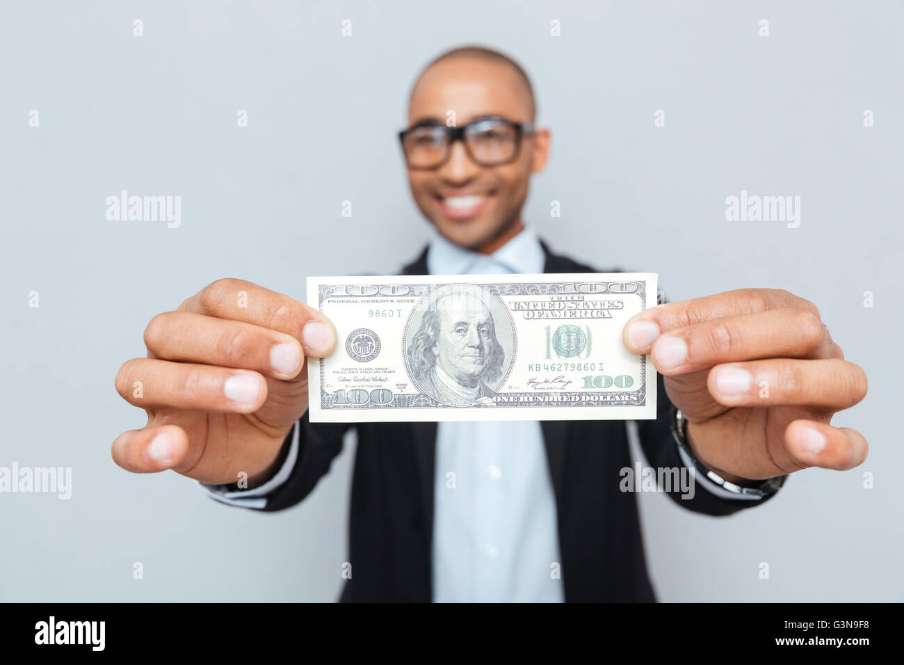 Smiling african american young man in glasses showing dollar banknote ...