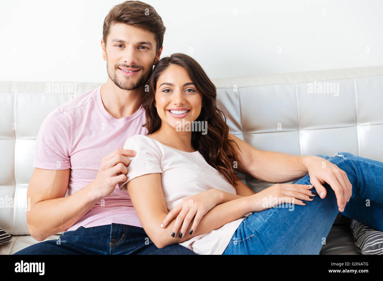 Happy smiling couple sitting on the couch over white background Stock ...