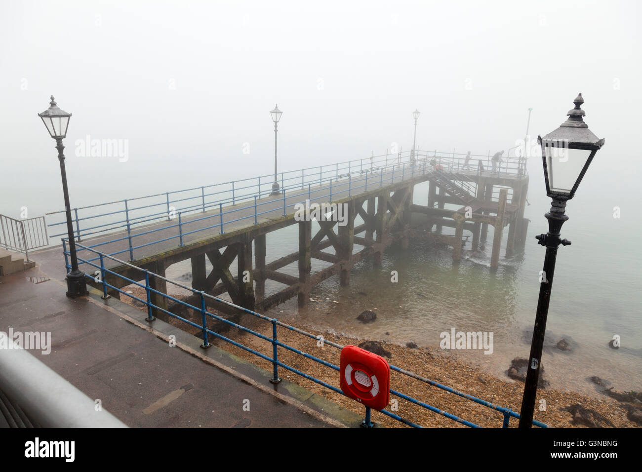 Portsmouth pier / jetty with street lamps and life preserver in fog ...