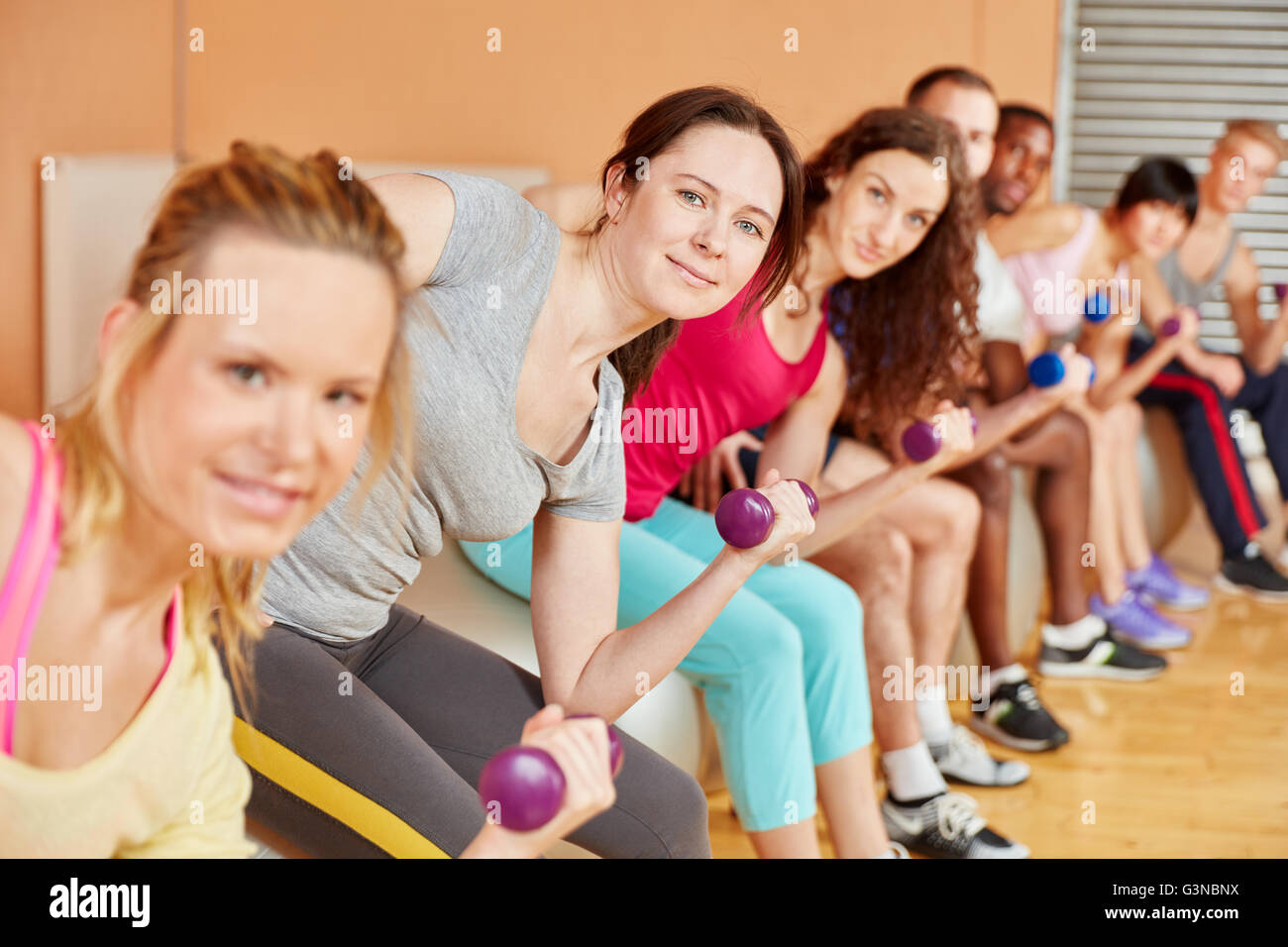 Women making exercise with weights during fitness class at the gym ...