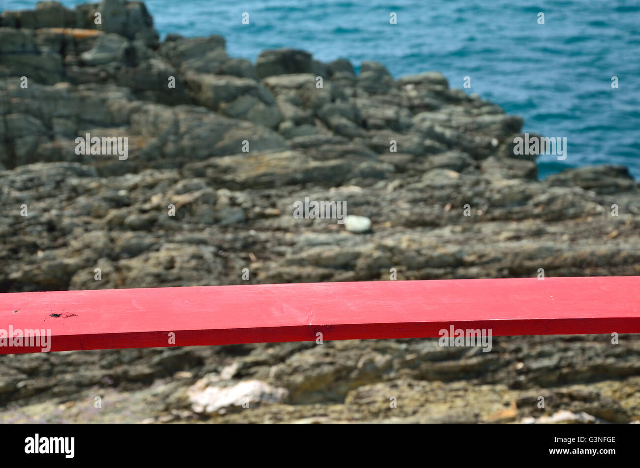 Red plank with rock and sea in background Stock Photo - Alamy