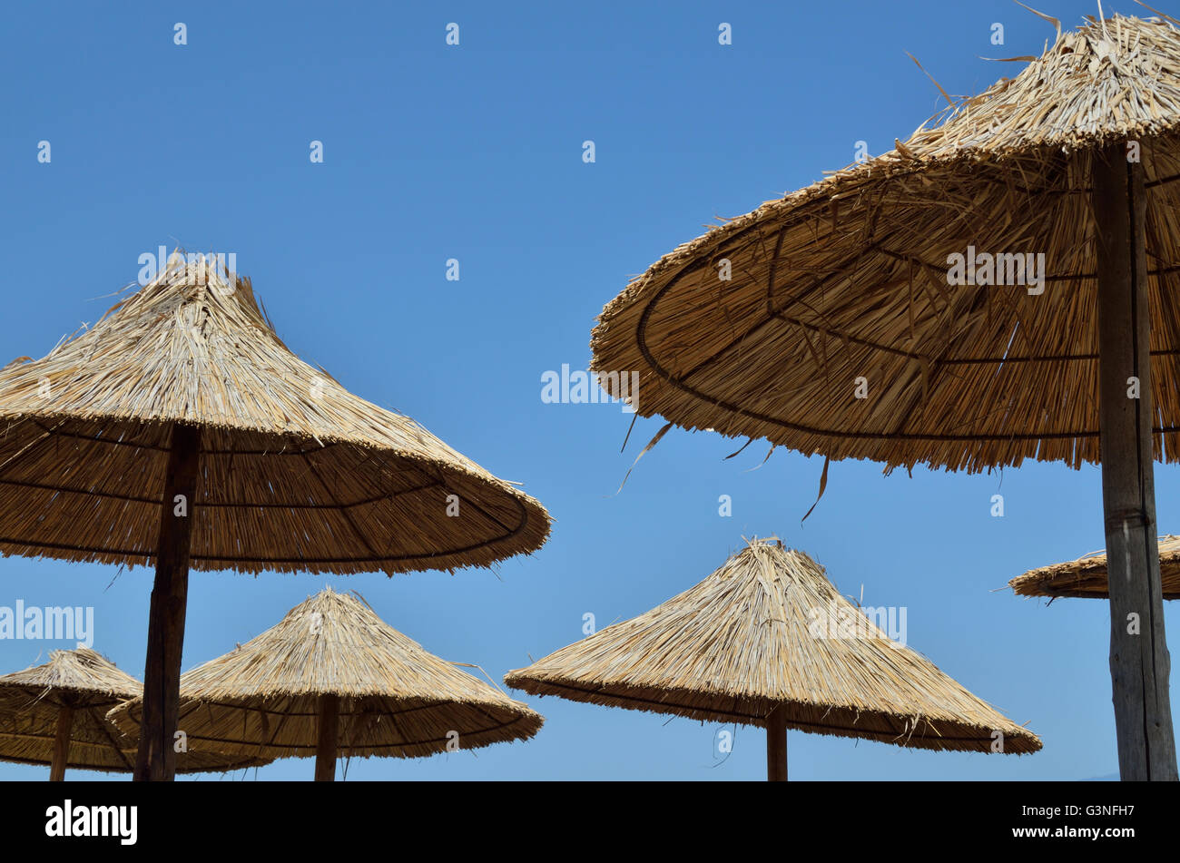 Beach straw parasols under clear blue sky Stock Photo - Alamy
